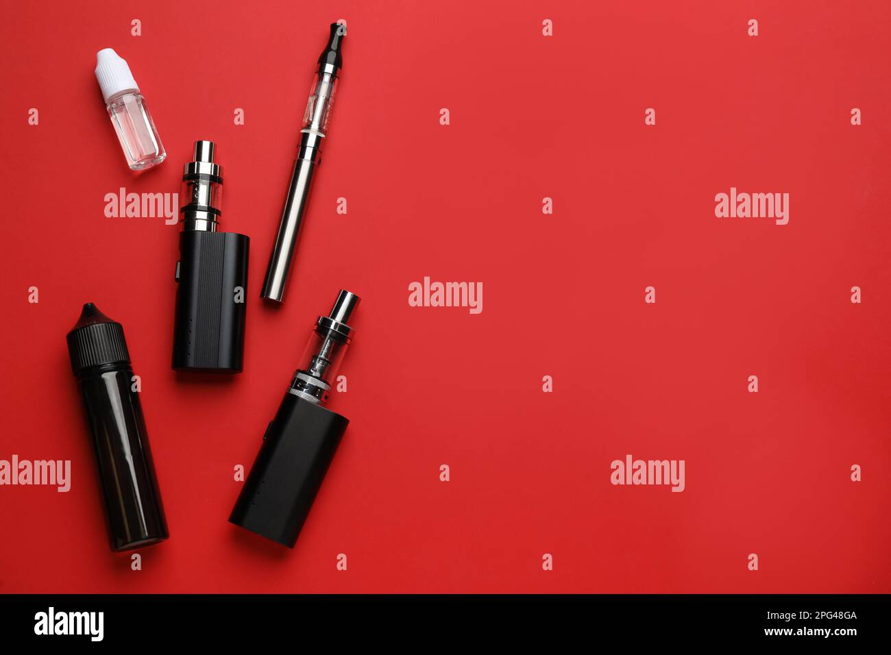 Many electronic smoking devices and vaping liquid on red background ...