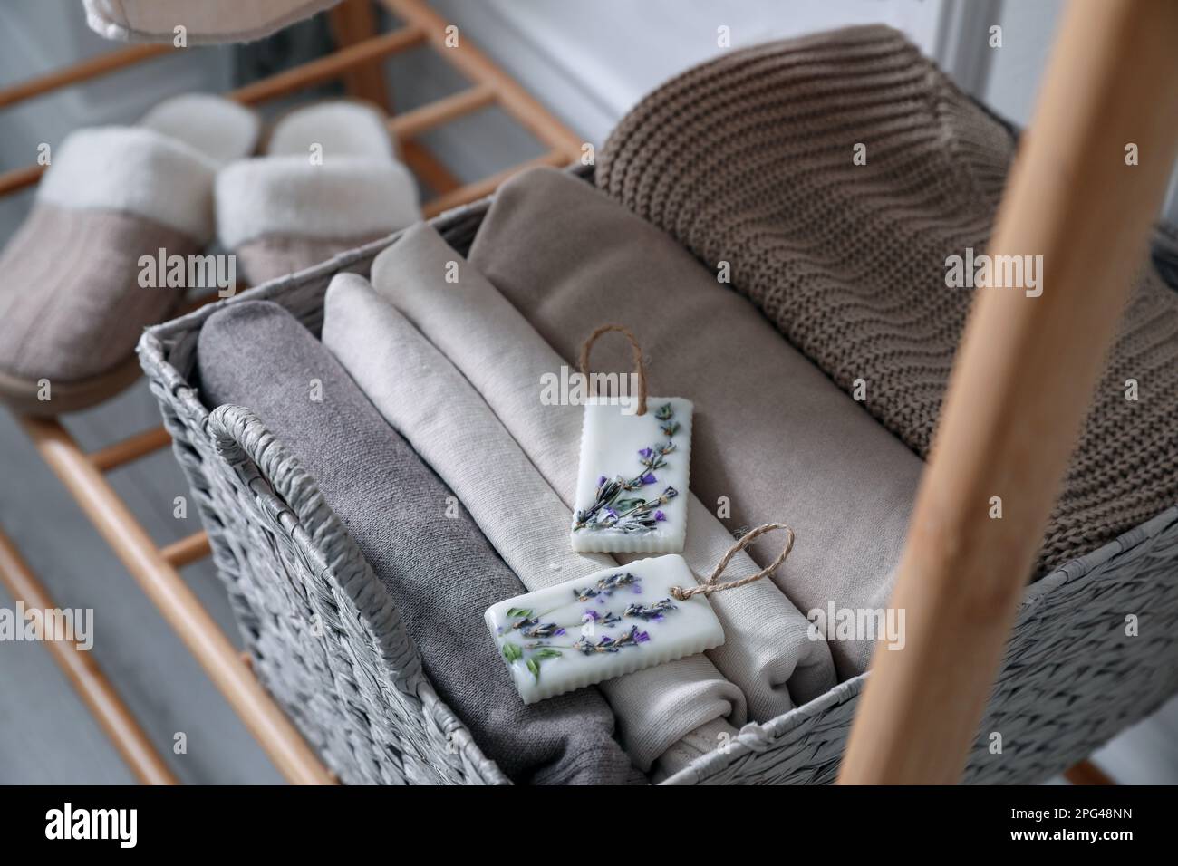 Beautiful scented wax sachets and folded clothes in wicker basket on ...