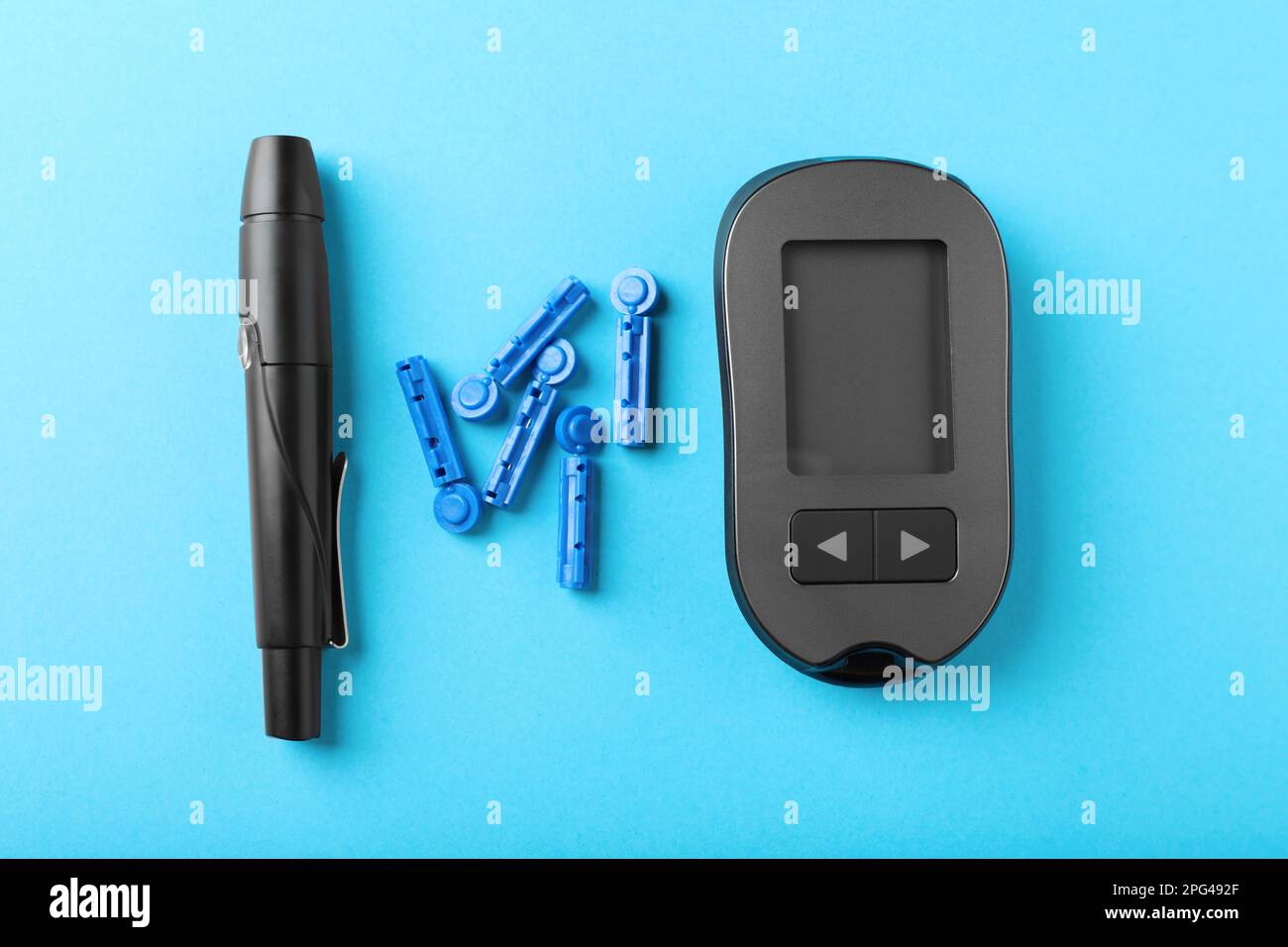 Digital glucometer, lancets and pen on light blue background, flat lay ...