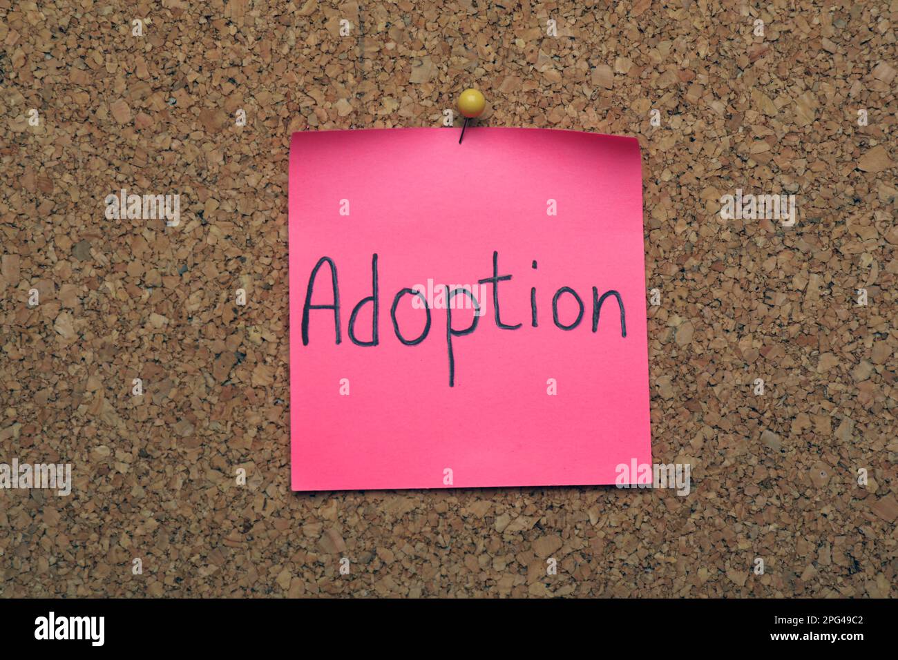 Note with word ADOPTION pinned to cork board Stock Photo - Alamy