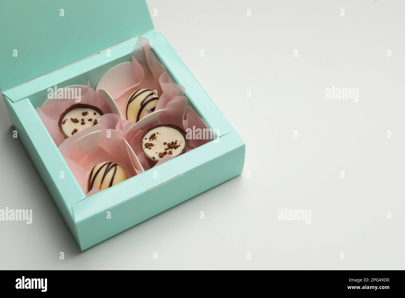 Delicious chocolate candies in turquoise box on light grey background ...