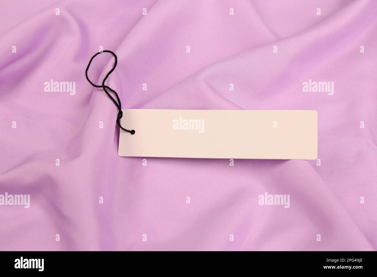 Blank white tag on violet fabric. Space or text Stock Photo - Alamy