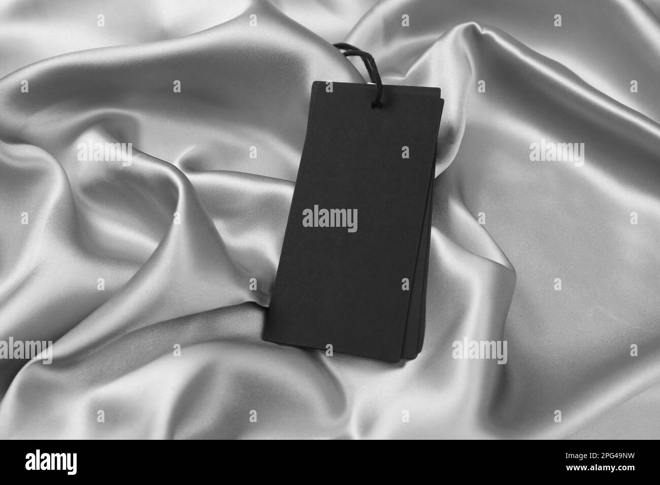 Blank black tags on silver silky fabric. Space for text Stock Photo - Alamy