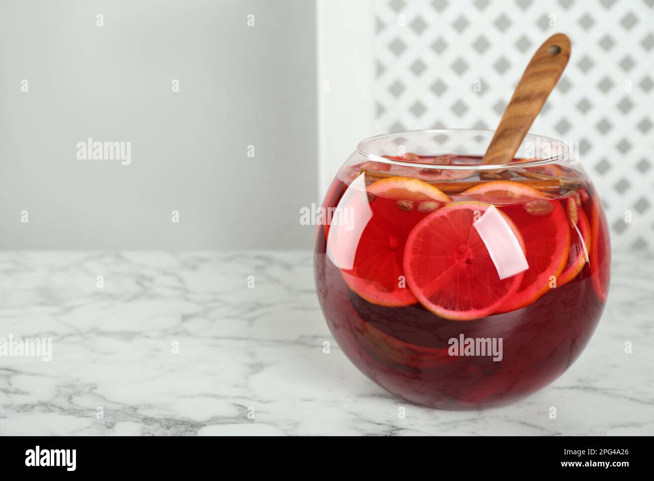 Glass bowl of aromatic punch drink on white marble table, space for ...