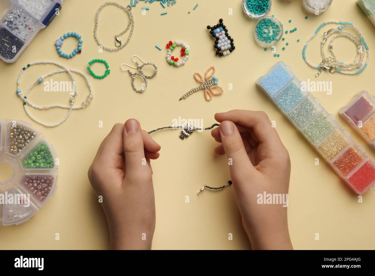 Girl making beaded jewelry on beige background, top view Stock Photo ...