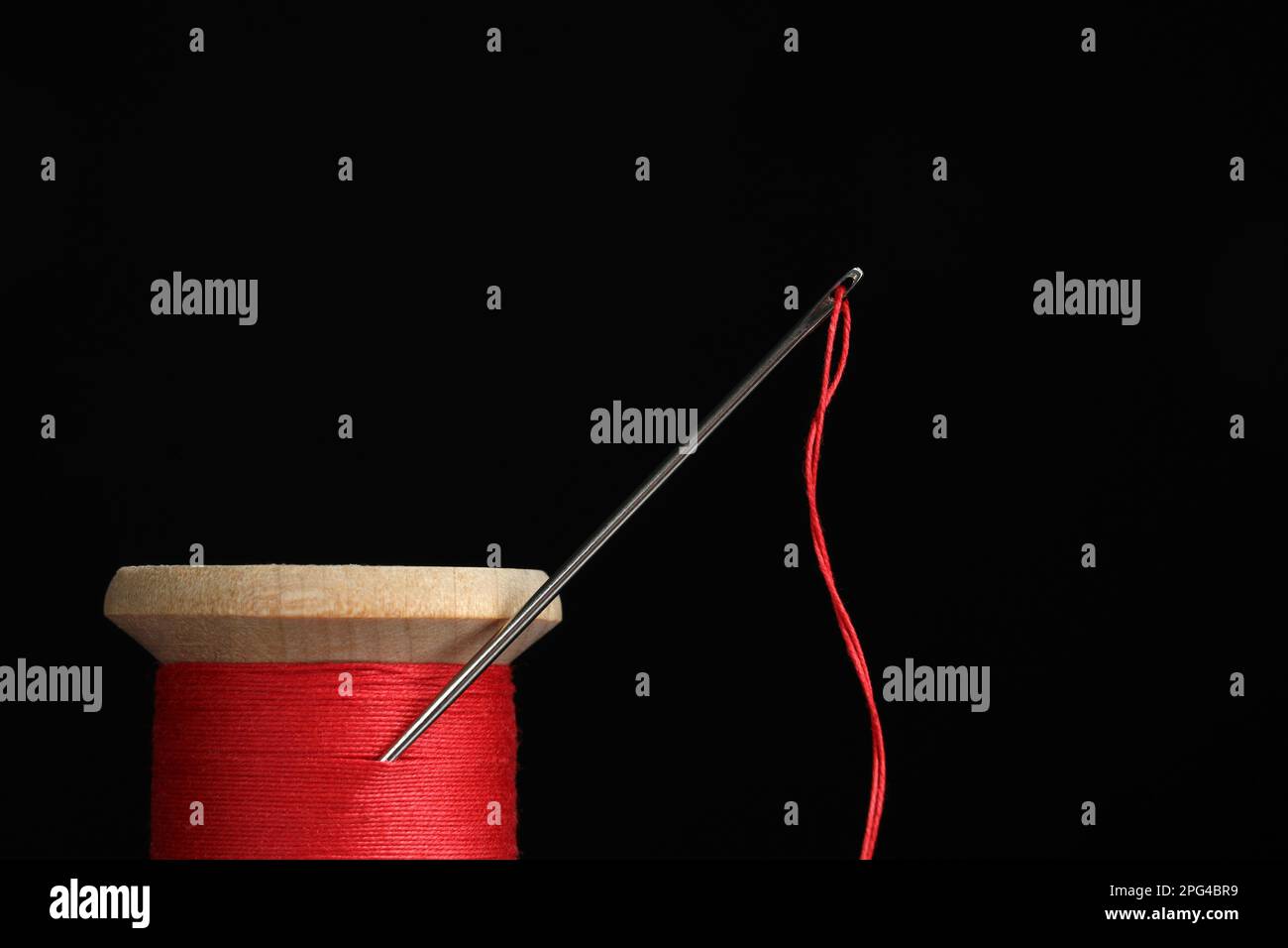 Red sewing thread with needle on black background, closeup Stock Photo ...