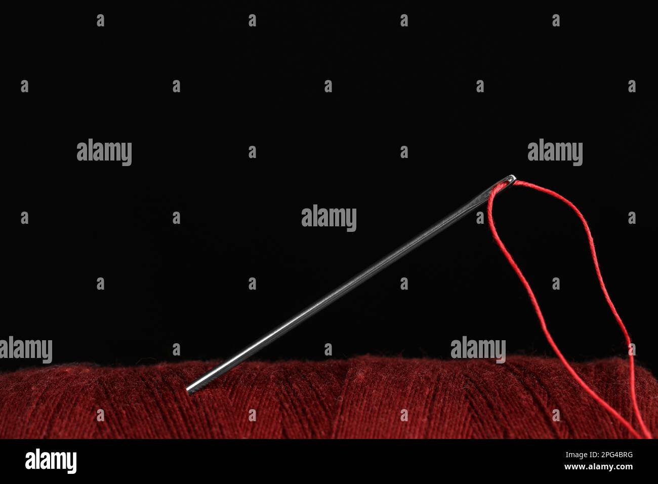 Red sewing thread with needle on black background, closeup Stock Photo ...