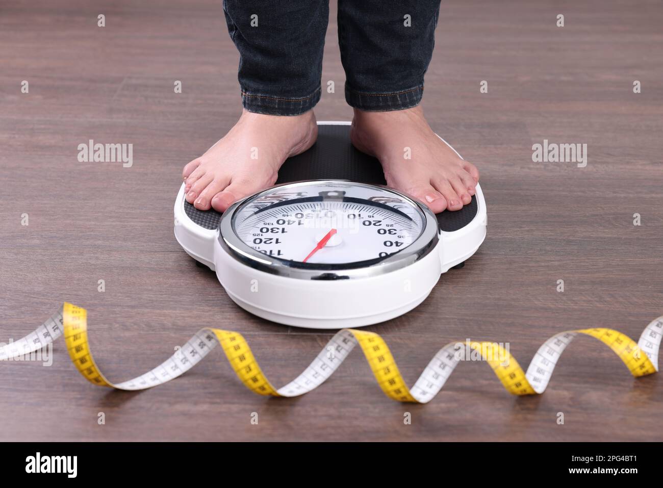 Woman using scales on floor near measuring tape, closeup. Overweight ...