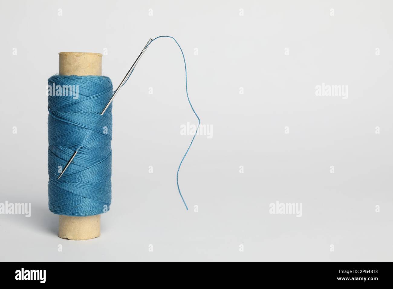 Light blue sewing thread with needle on white background Stock Photo ...