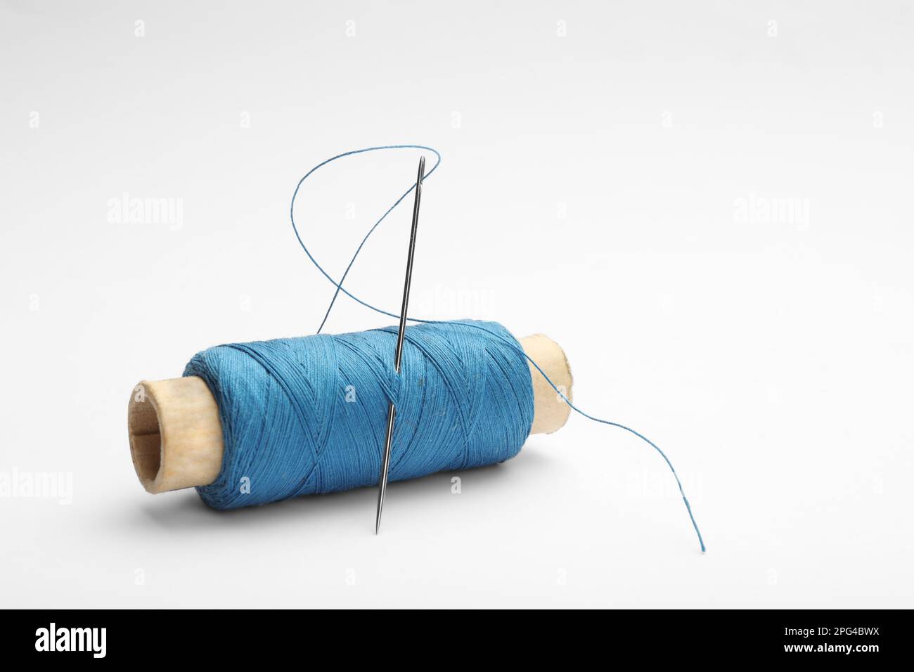 Light blue sewing thread with needle on white background Stock Photo ...