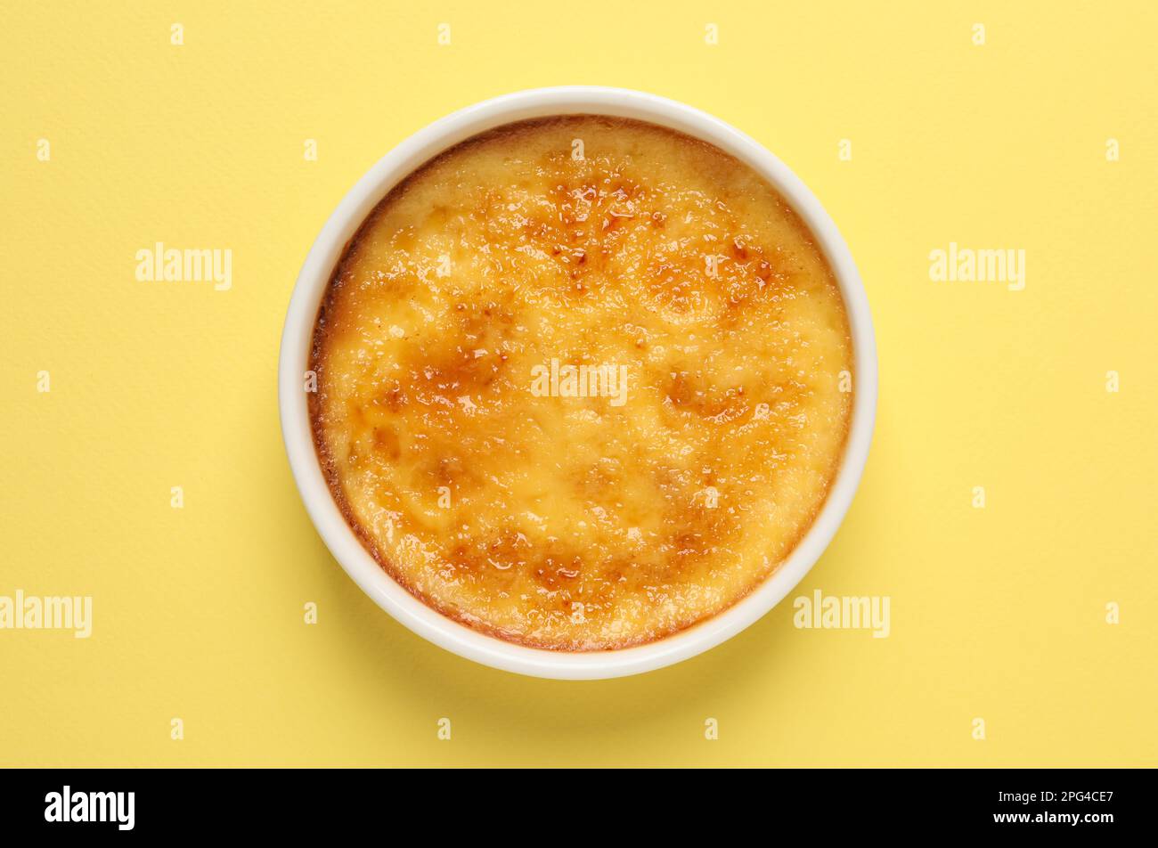 Delicious creme brulee in ceramic ramekin on yellow background, top ...