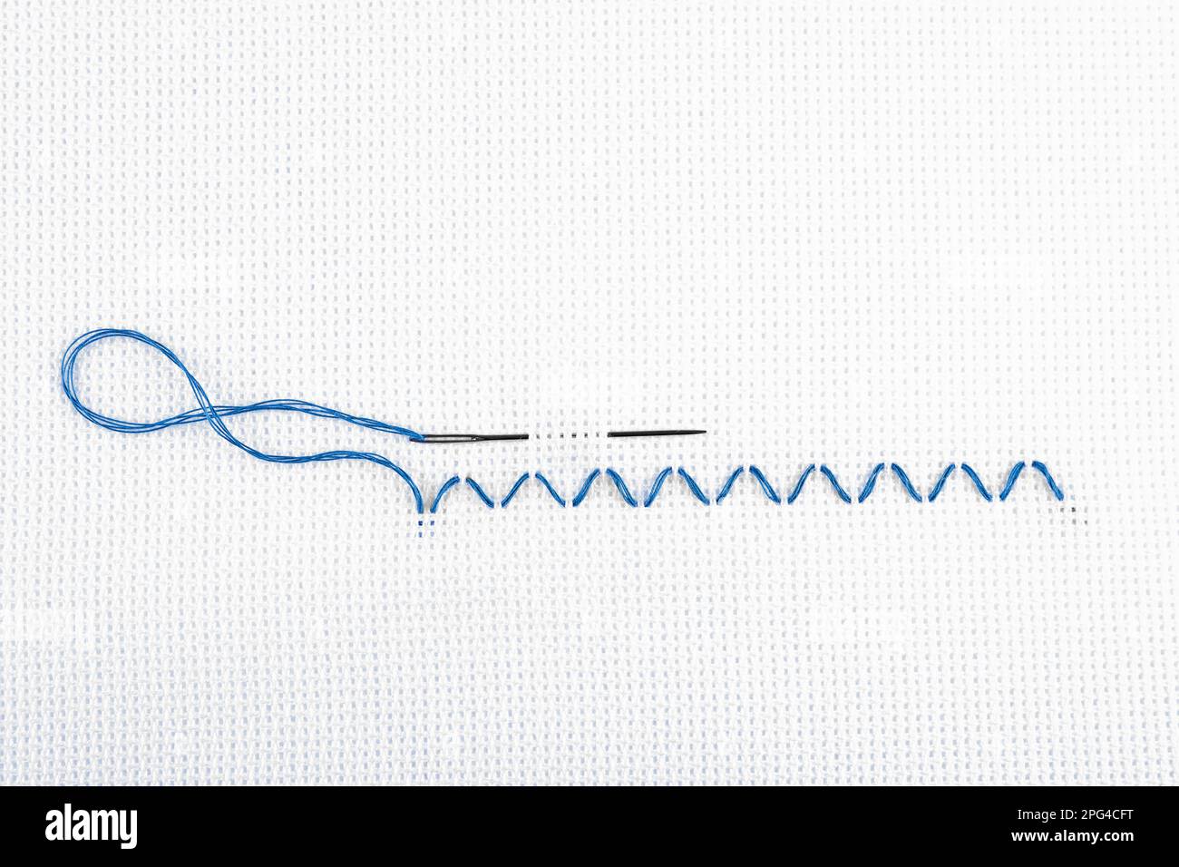 Embroidery stitches made with blue thread and needle on canvas, top ...