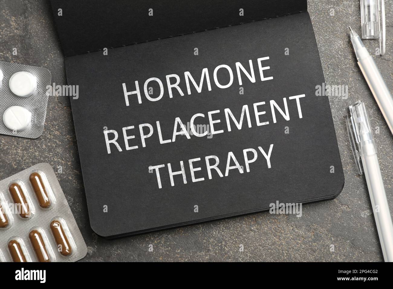 Black notebook with text Hormone Replacement Therapy, pills and pens on ...