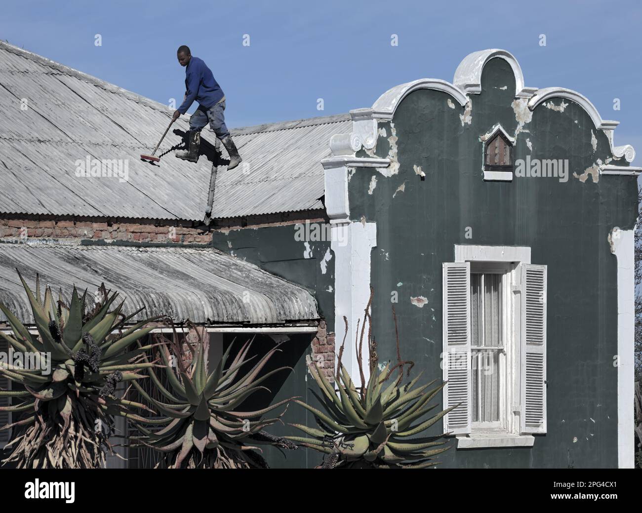 Man cleaning roof for restoration of typical old Karoo homestead ...