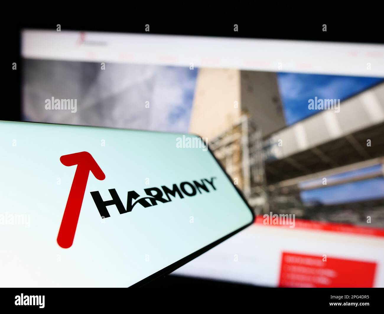 Mobile phone with logo of company Harmony Gold Mining Co. Ltd. on screen in front of business ...