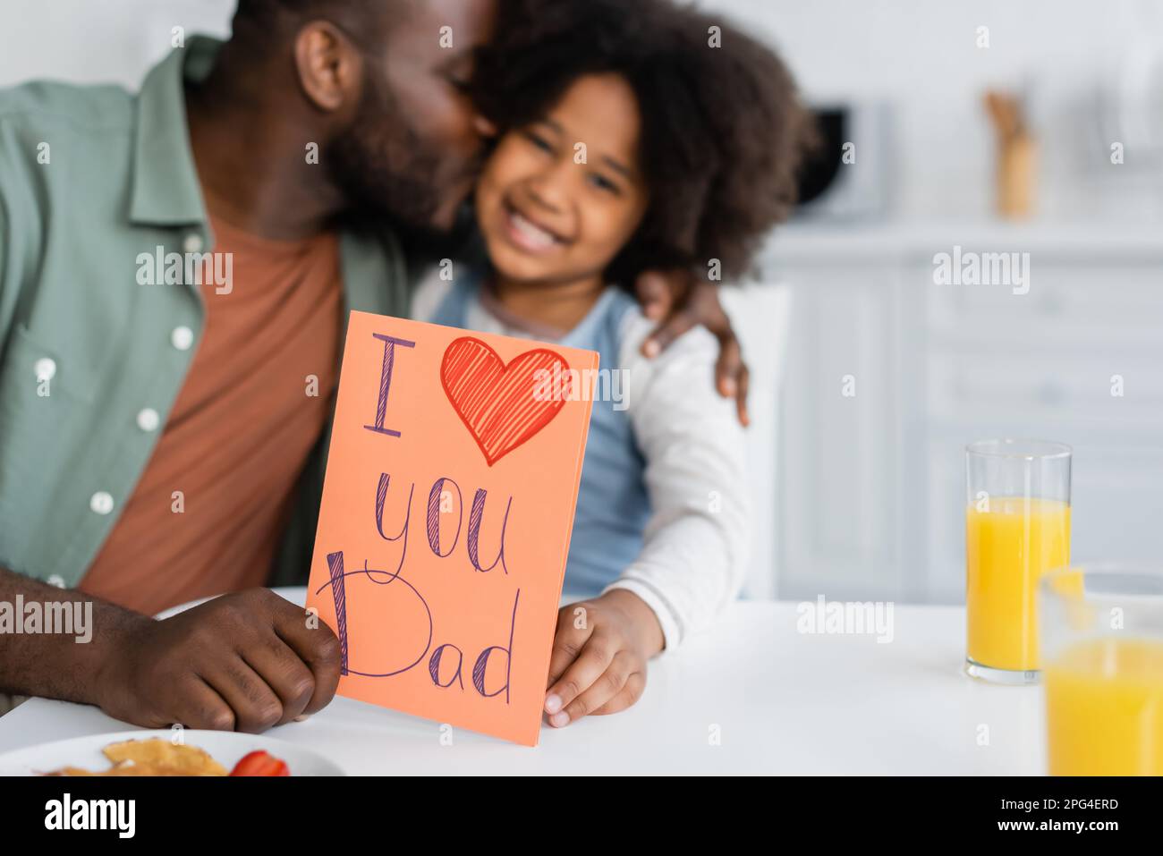 african american man kissing daughter and holding greeting card with i ...