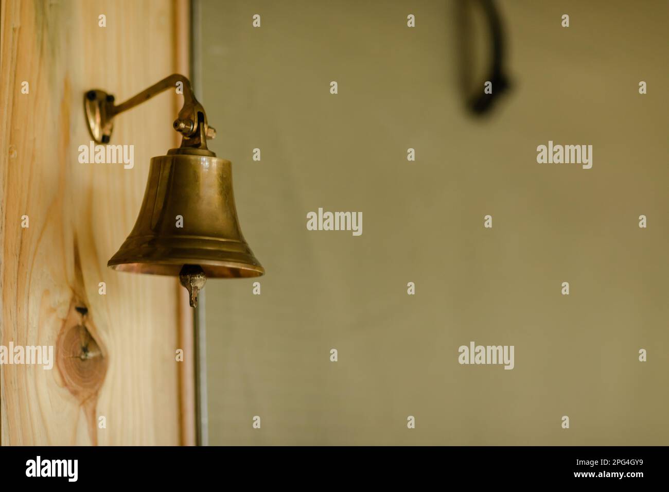 A closeup image of a golden bell hanging from a wall Stock Photo - Alamy