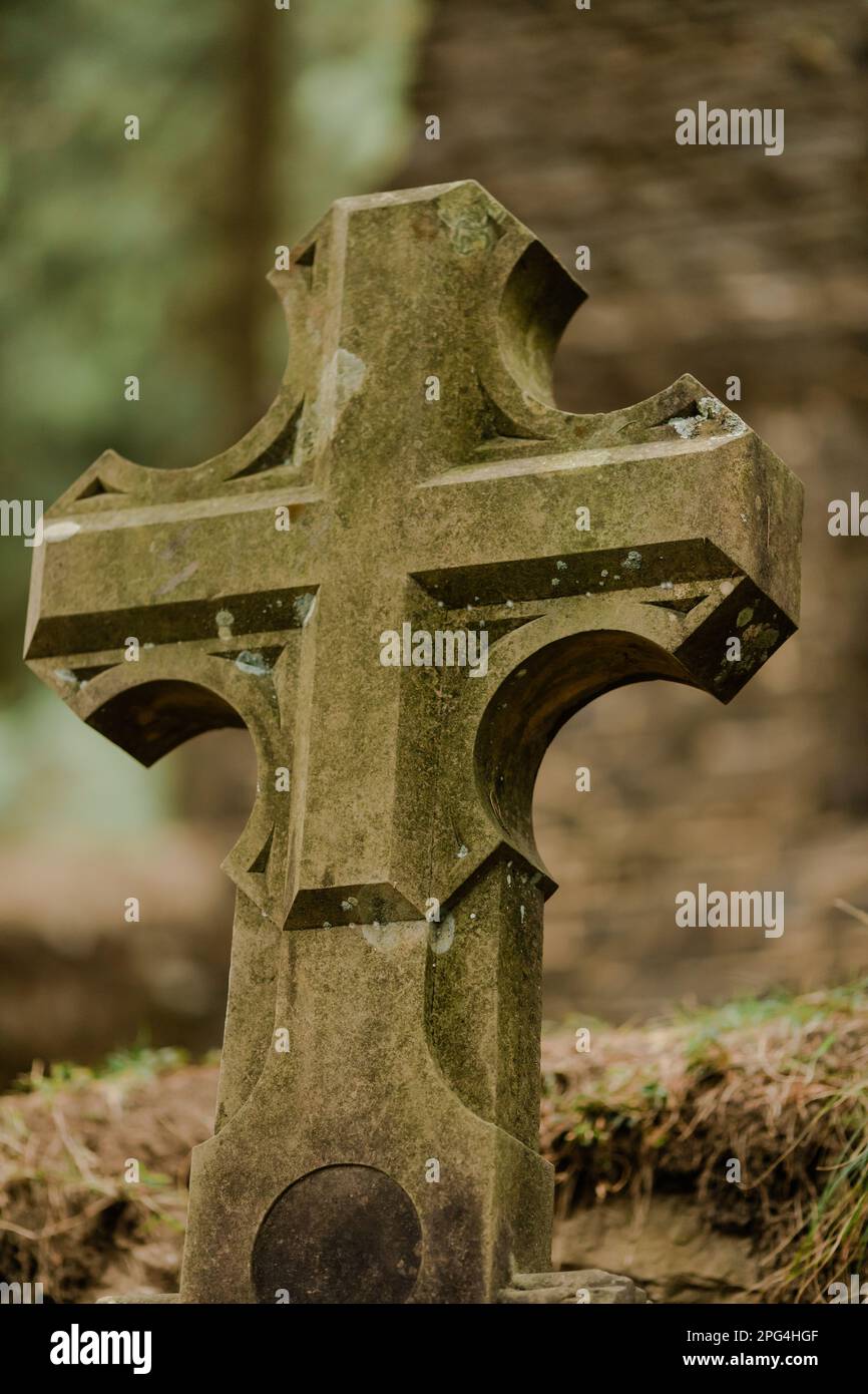 An antique stone cross situated on a gravel pathway in a tranquil park ...