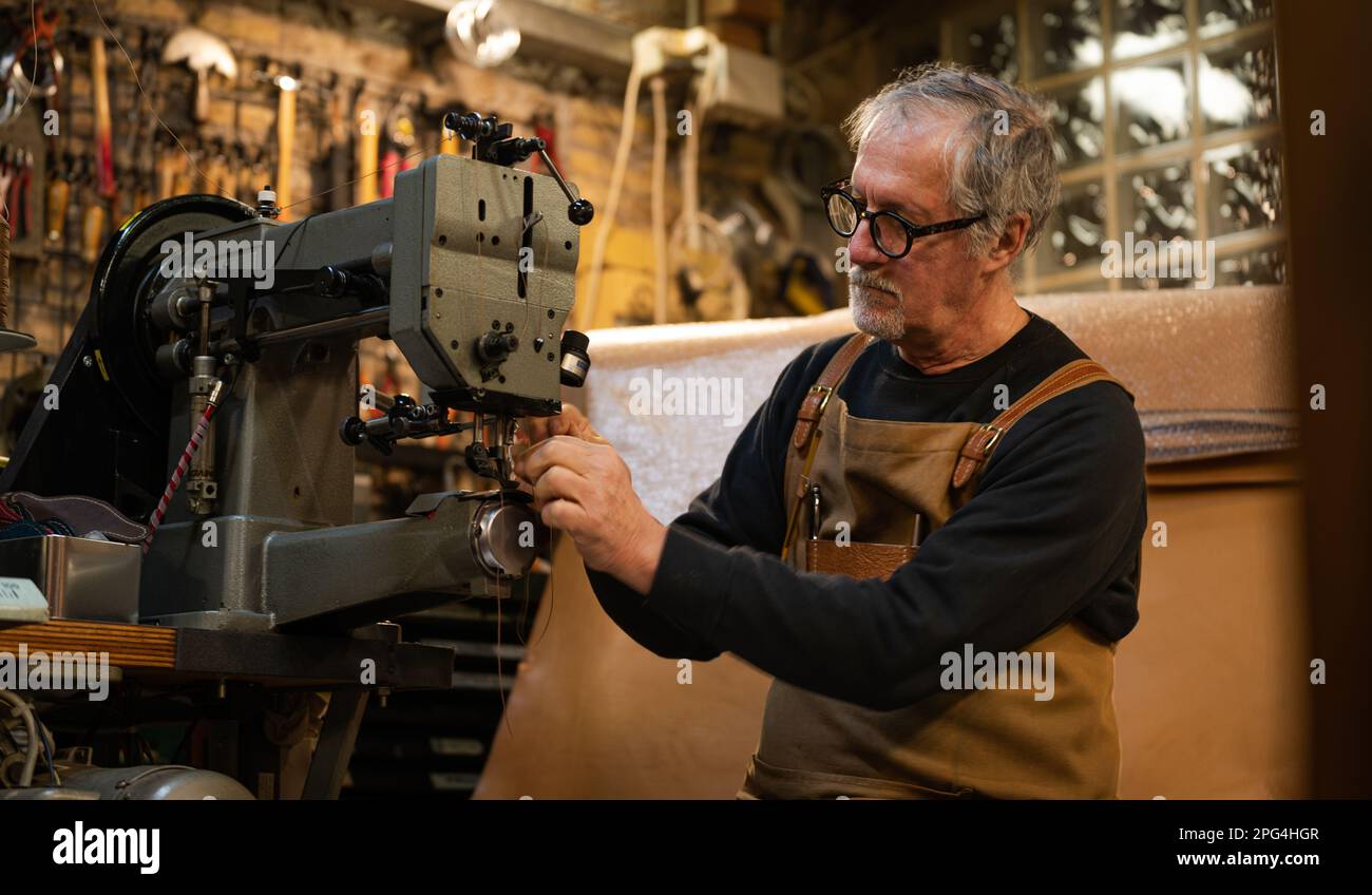 adult craftsman sitting adding thread in a sewing machine to start ...