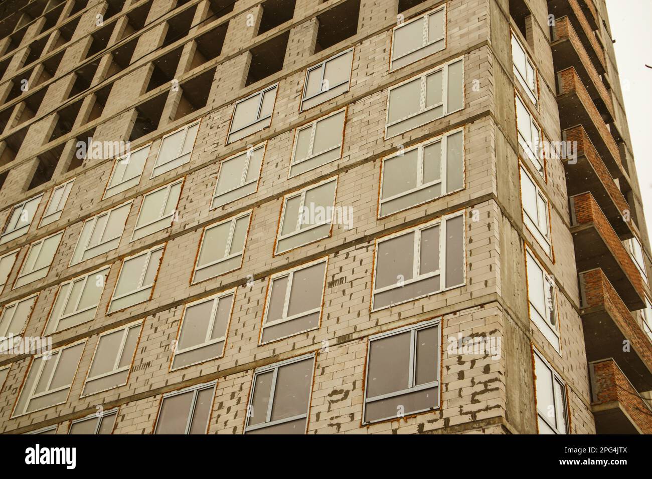 Glazing a brick facade of an unfinished high-rise apartment building on ...