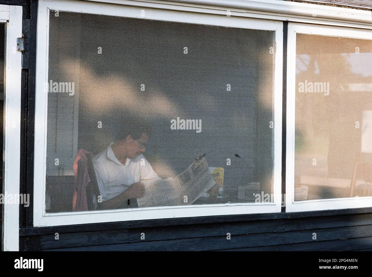 guest relaxes reading newspaper on the screened in porch of cottage in ...