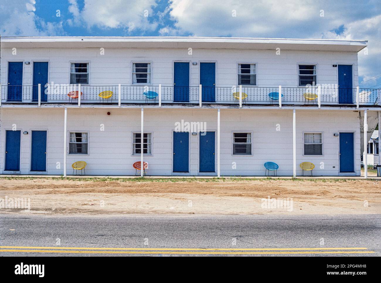 Seaside motel with colorful vintage plastic chairs on balcony faces the ...