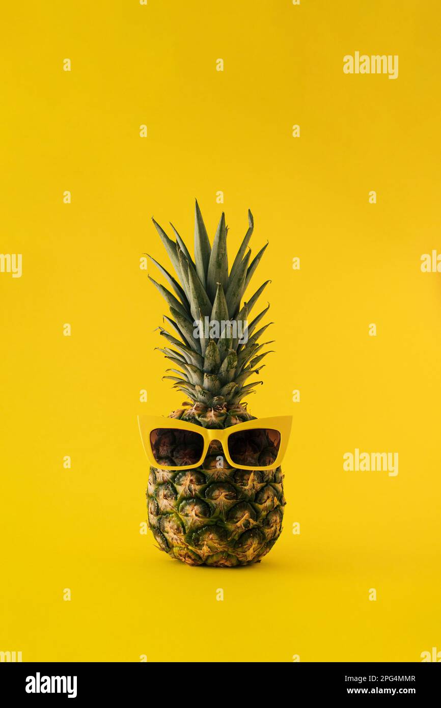 Fresh pineapple with sunglasses on yellow background. Minimal summer ...