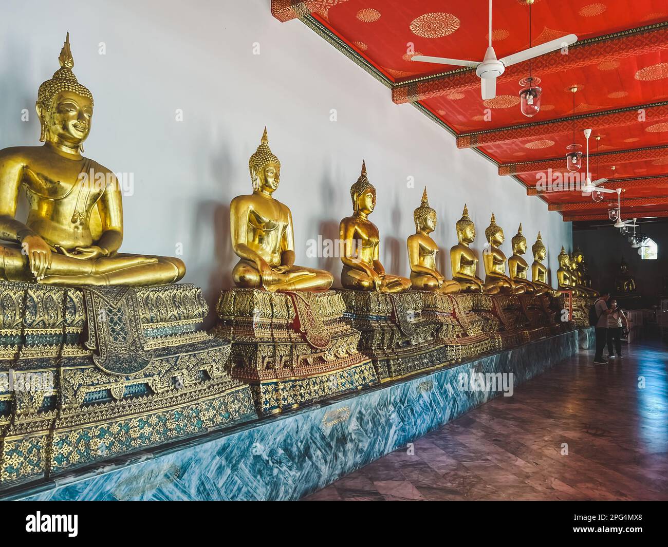 A row of statues of the Buddha illuminated by light shining through a ...
