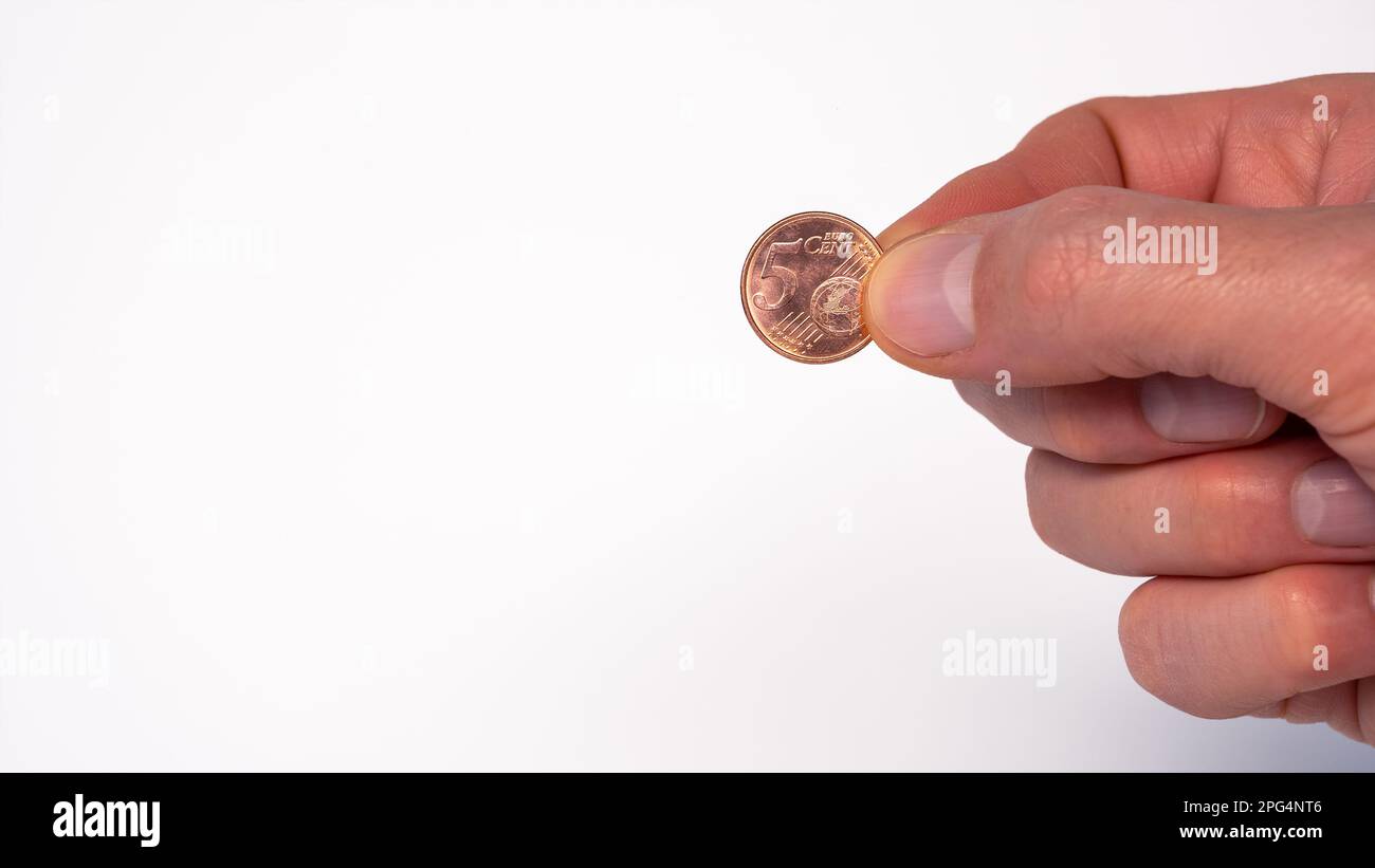 Copper 5 Euro Cent coin between the fingers of the hand of a woman ...