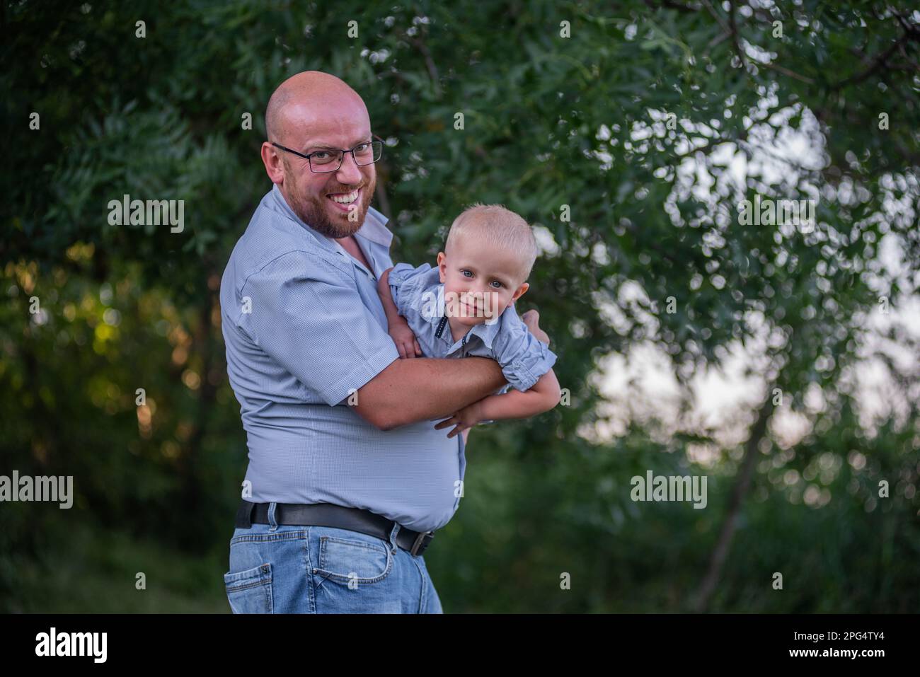 Bald man with glasses throws child into the sky air. Father in jeans ...