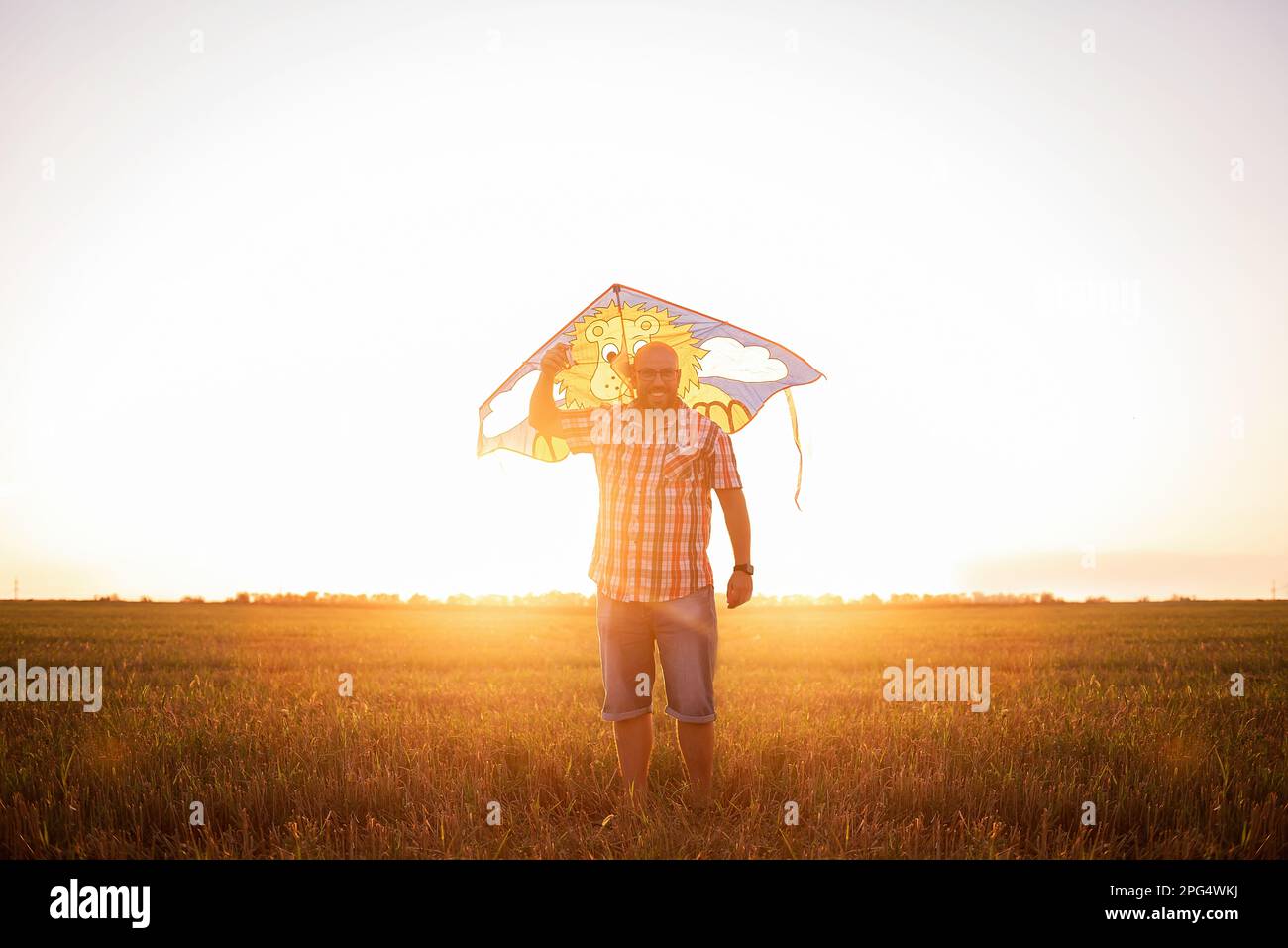 In the rays of the sunset sun, bald man with glasses with kite in the ...