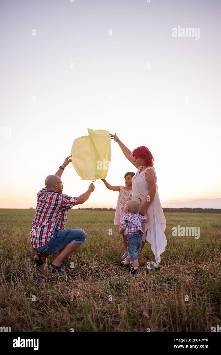 Diversity family launch yellow sky lantern in field at sunset. Mother ...