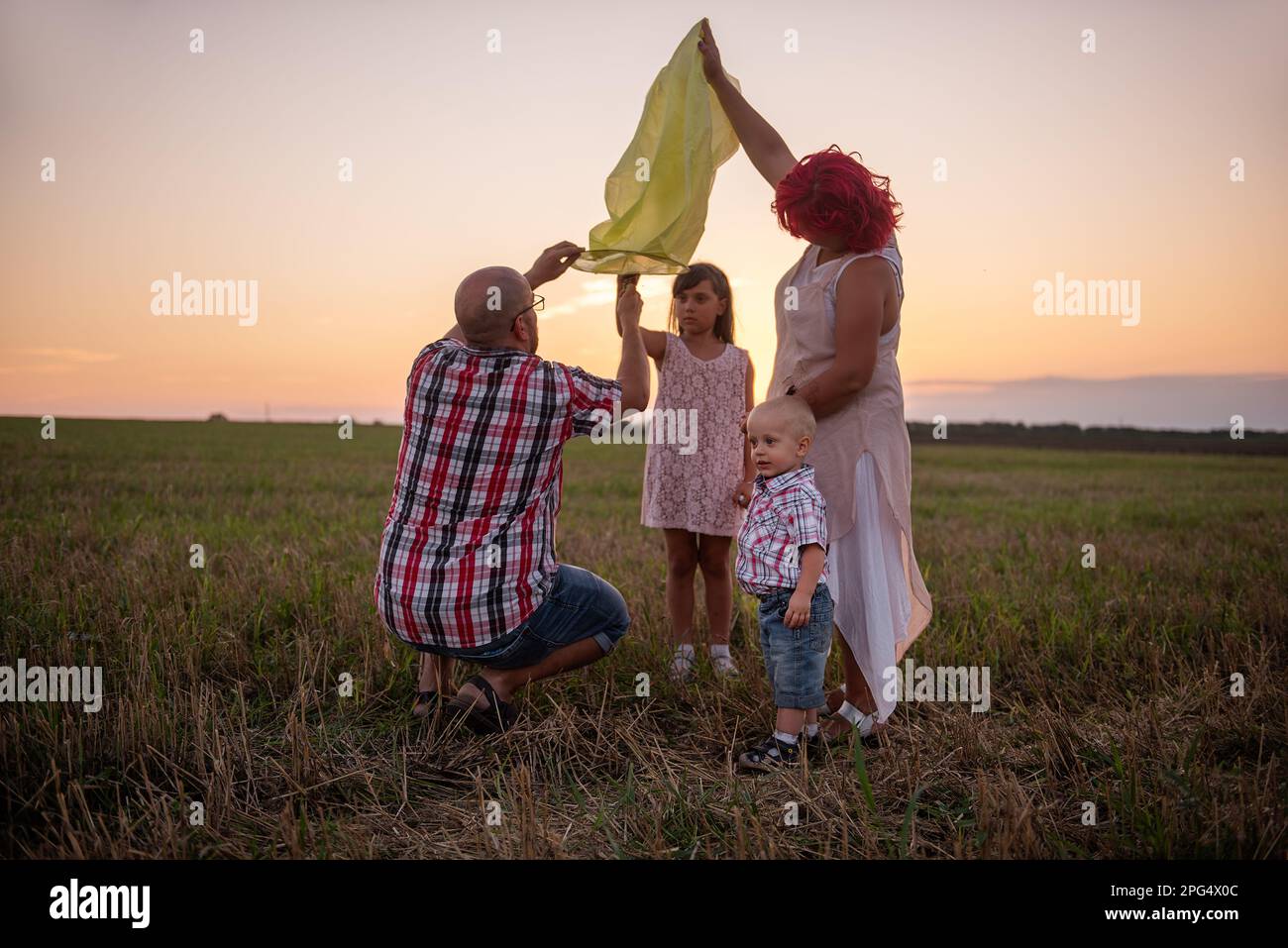 Diversity family launch yellow sky lantern in field at sunset. Mother ...