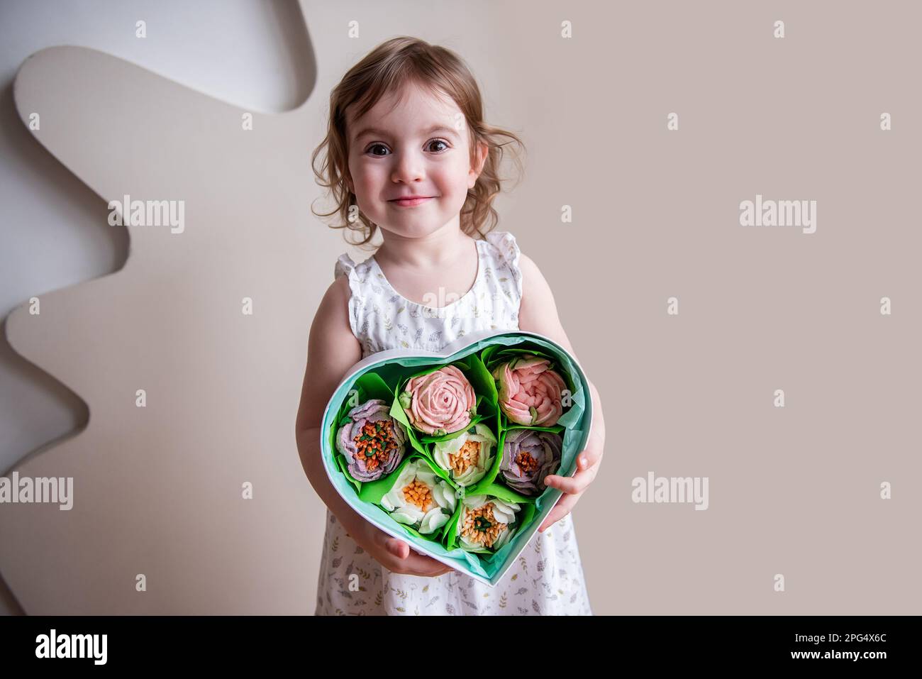 Little curly girl holds heart shaped box with homemade, sweet ...