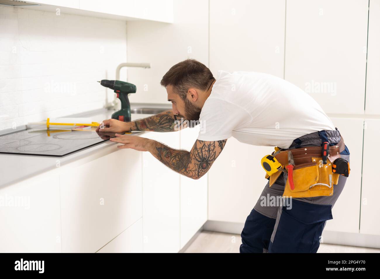 Man electrical repairs kitchen surface apartment. Installing hob in ...