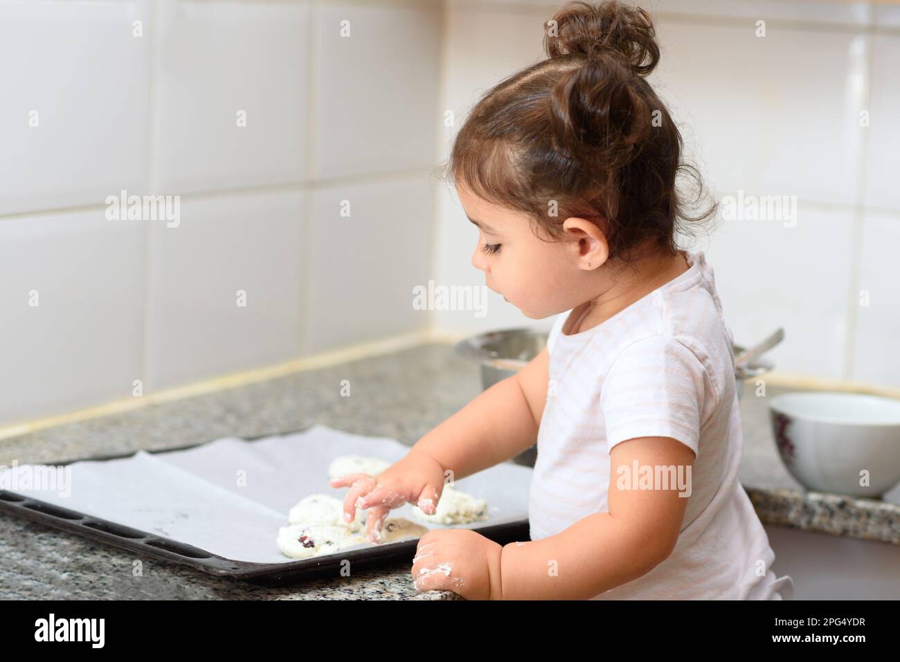 Little kid girl making pancakes on marble table. Happy family funny ...