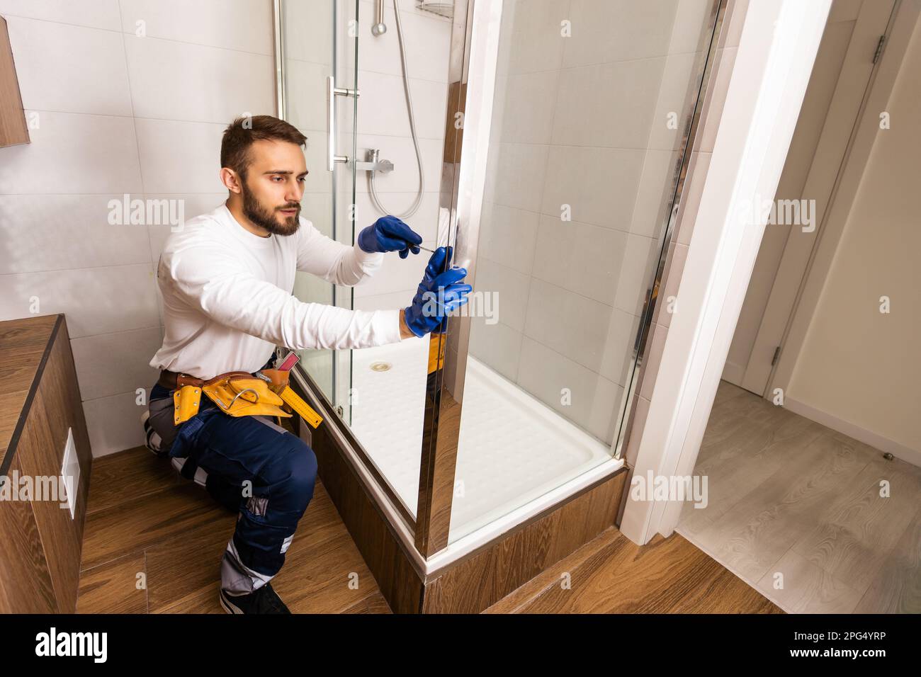 The worker is connecting the glass walls of the shower enclosure with a ...