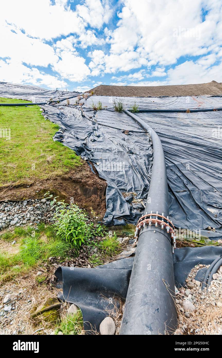 A large pipe with bolted flange connectors lays uphill over a ...