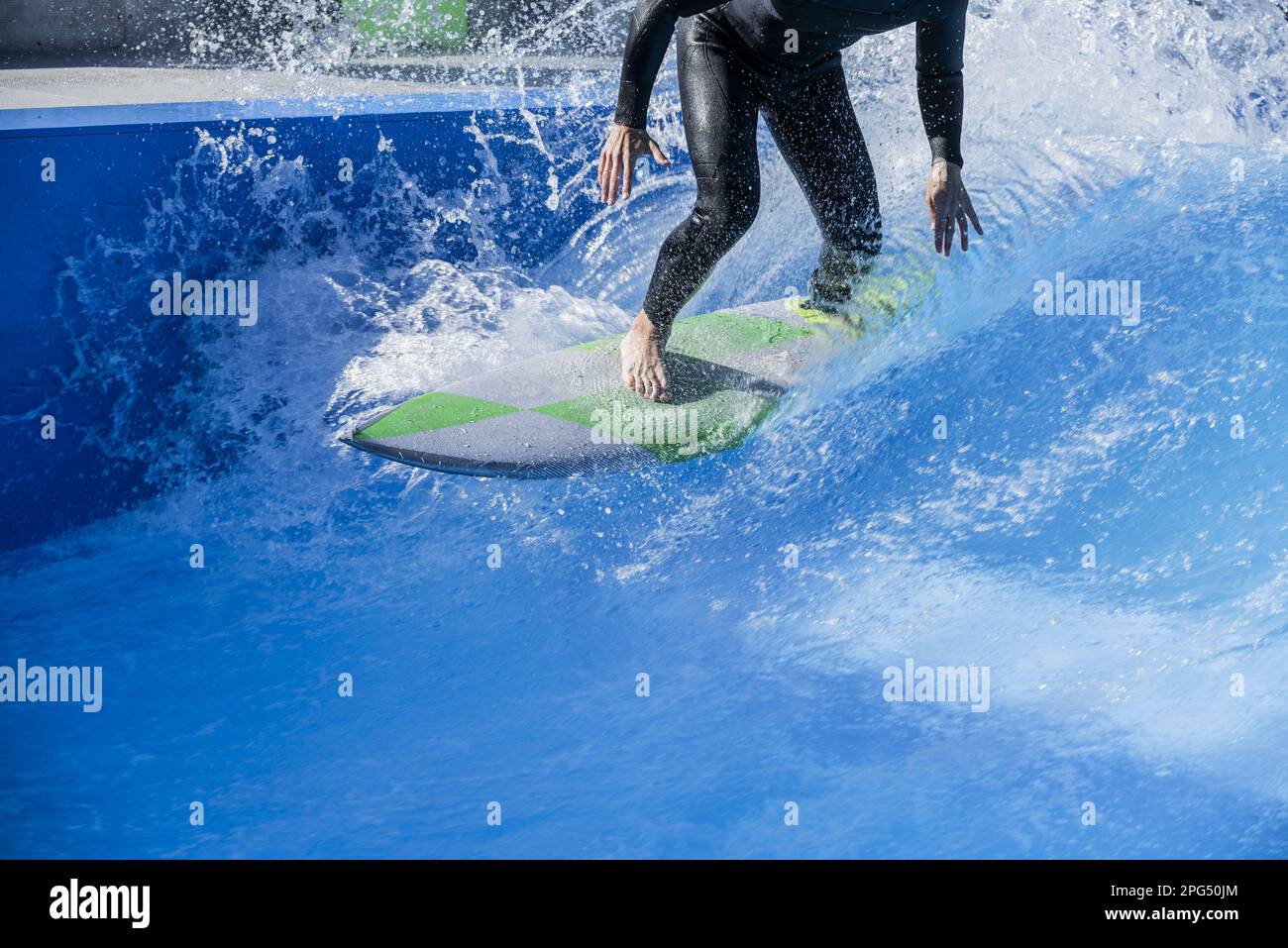 A surfer dressed in his black neoprene suit raising foam in the waves ...