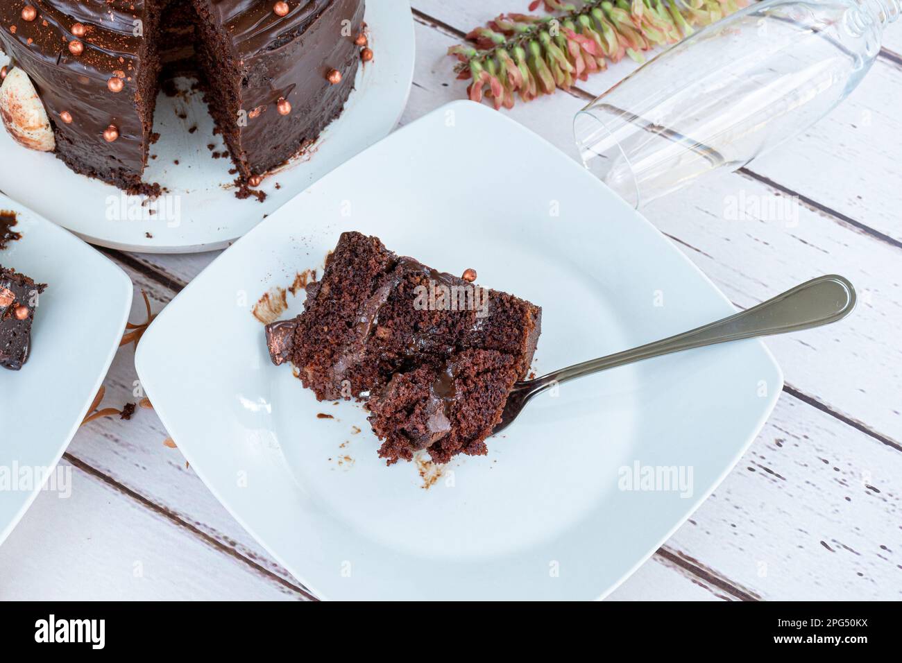 Slice of chocolate cake with dark ganache filling next to a fork top ...