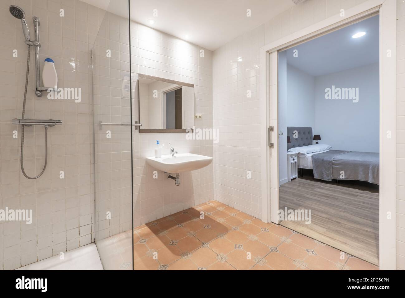 A large unfurnished washroom with a floating porcelain sink, glass ...
