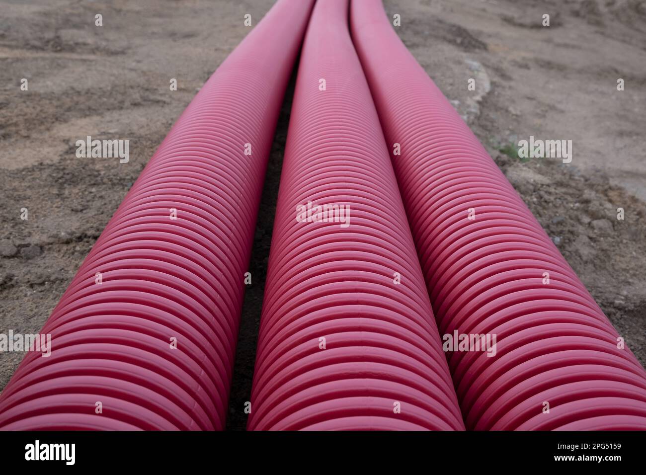red corrugated pipe are buried underground on the street. underground ...