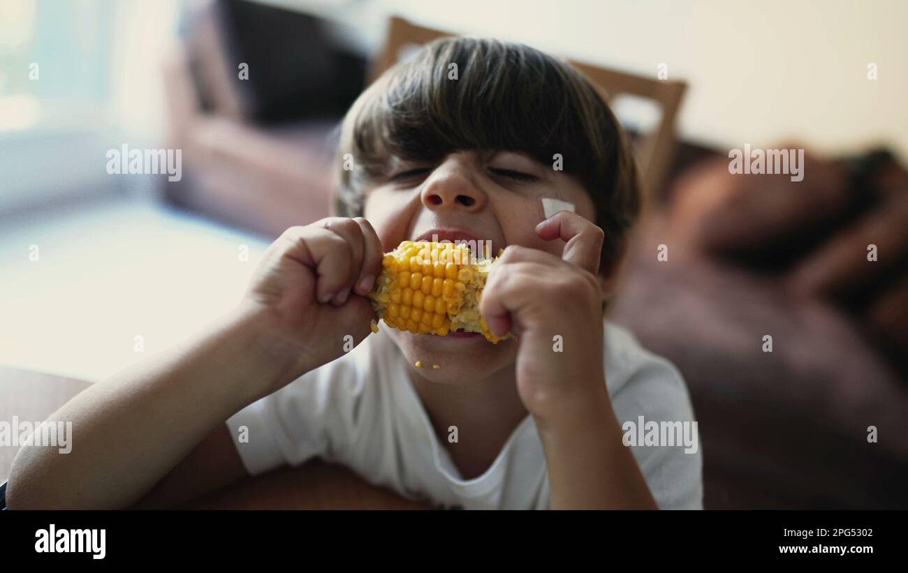 Child eating CORN at home. One little boy snacking nutritious FOOD ...