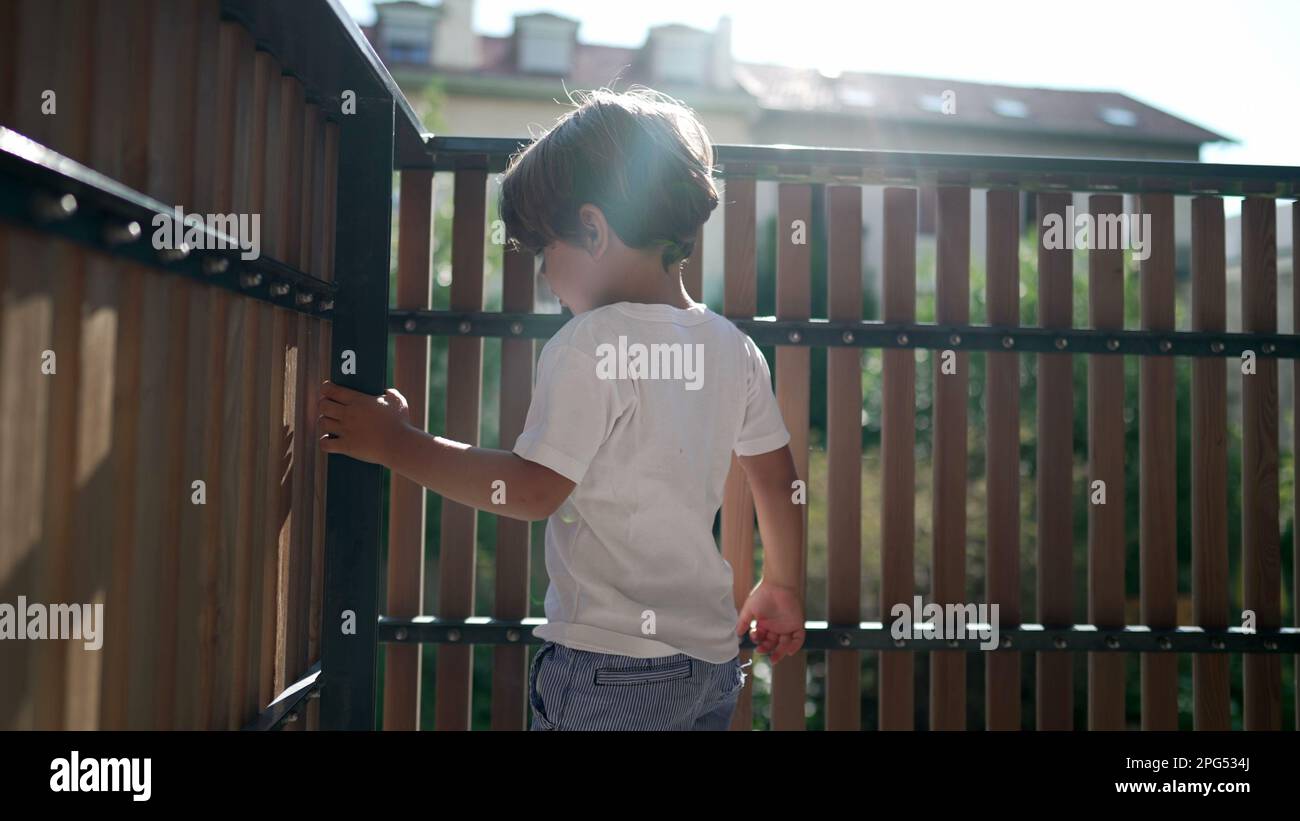 One playful little boy standing at apartment balcony in sunlight. Child ...