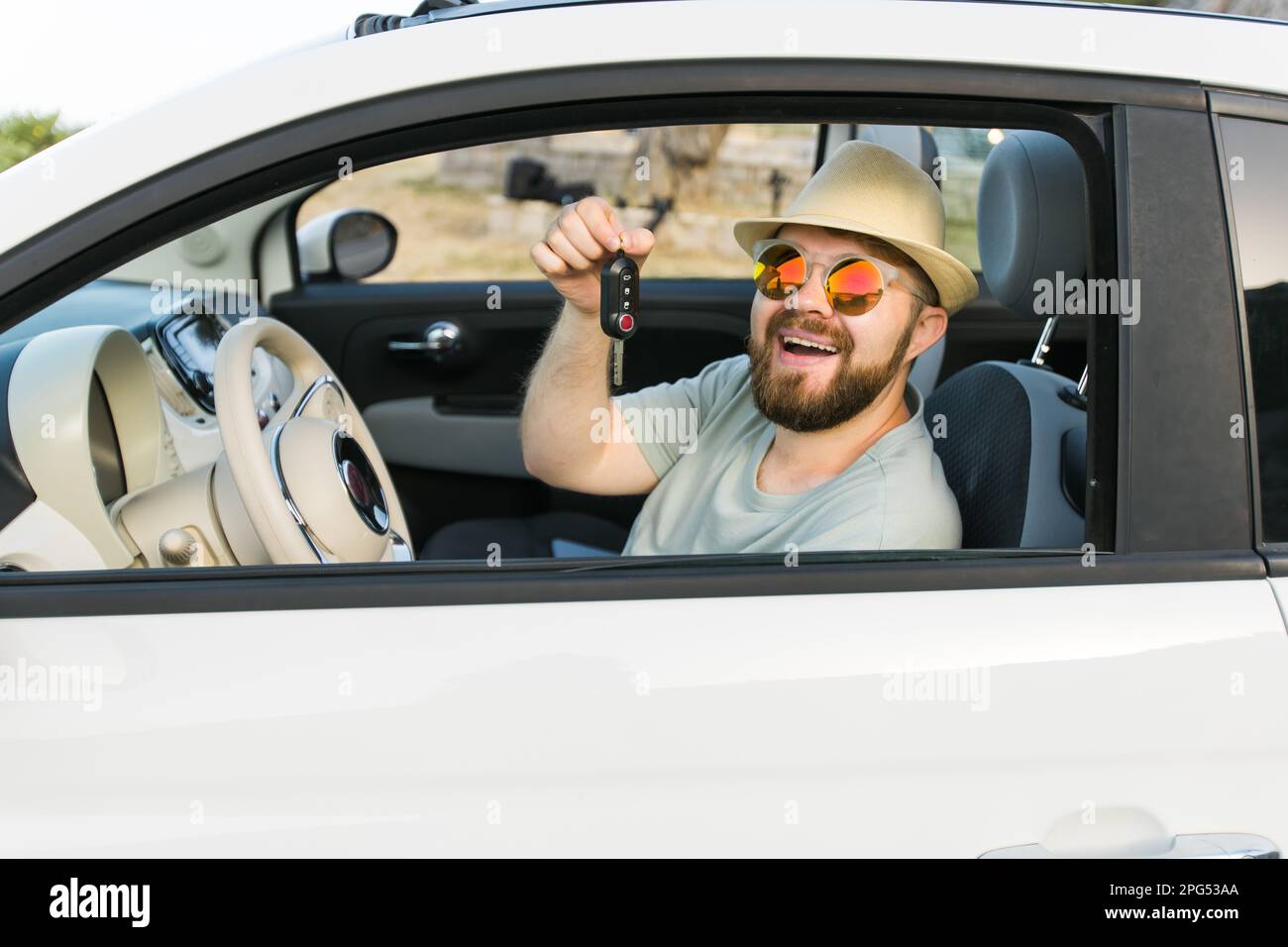 Car driver man smiling showing new car keys and car. Bearded guy ...
