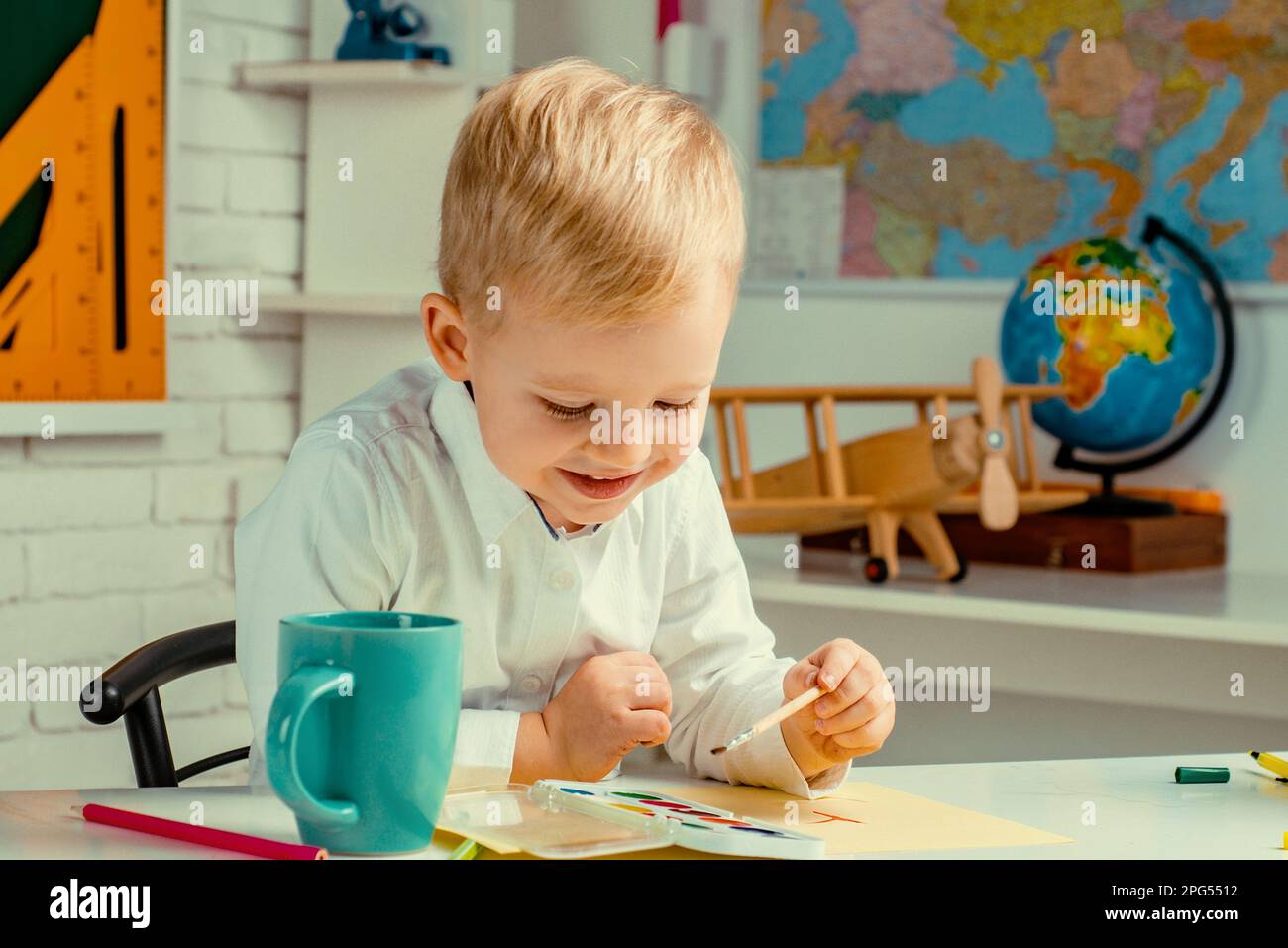 Portrait of smiling schoolboy doing his homework in classroom at school ...