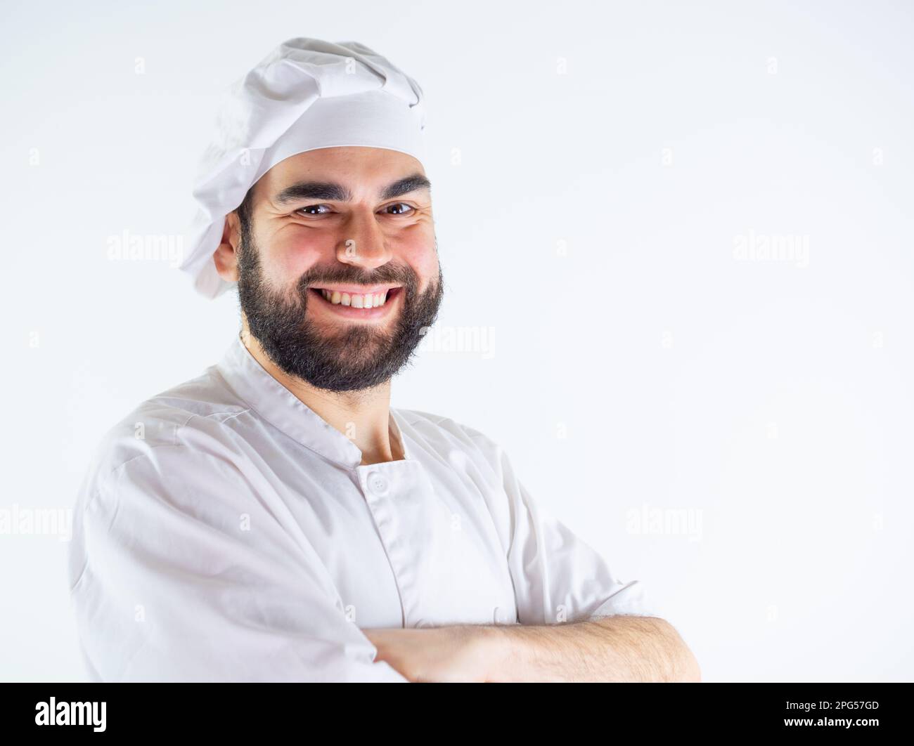 Young male chef portrait with arms crossed while smiling and looking at ...