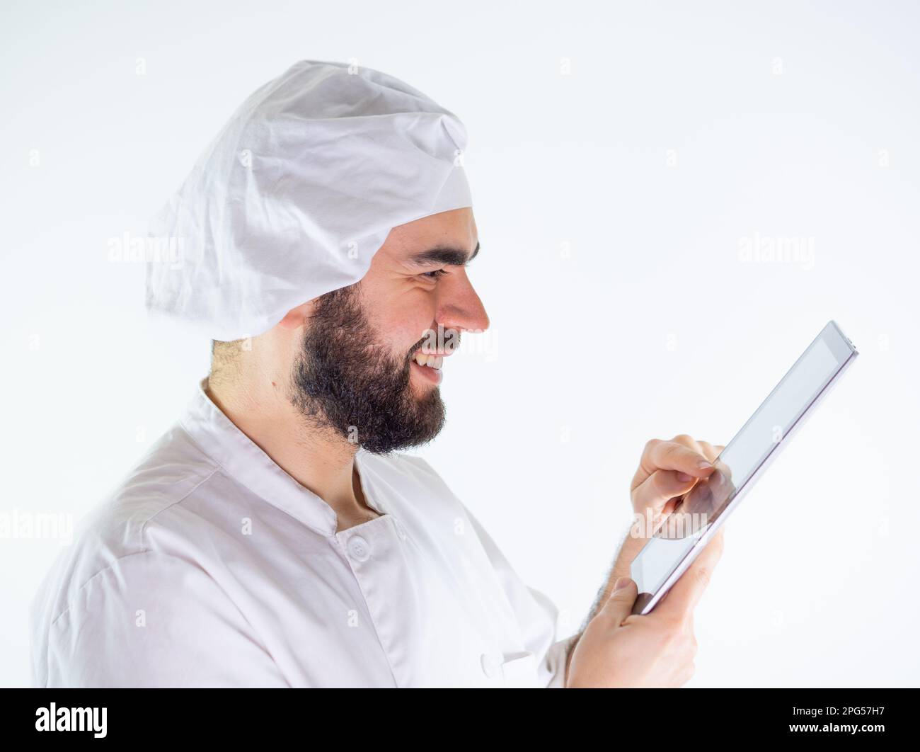 Young male chef using a tablet, reading a recipe. Isolated on a white ...