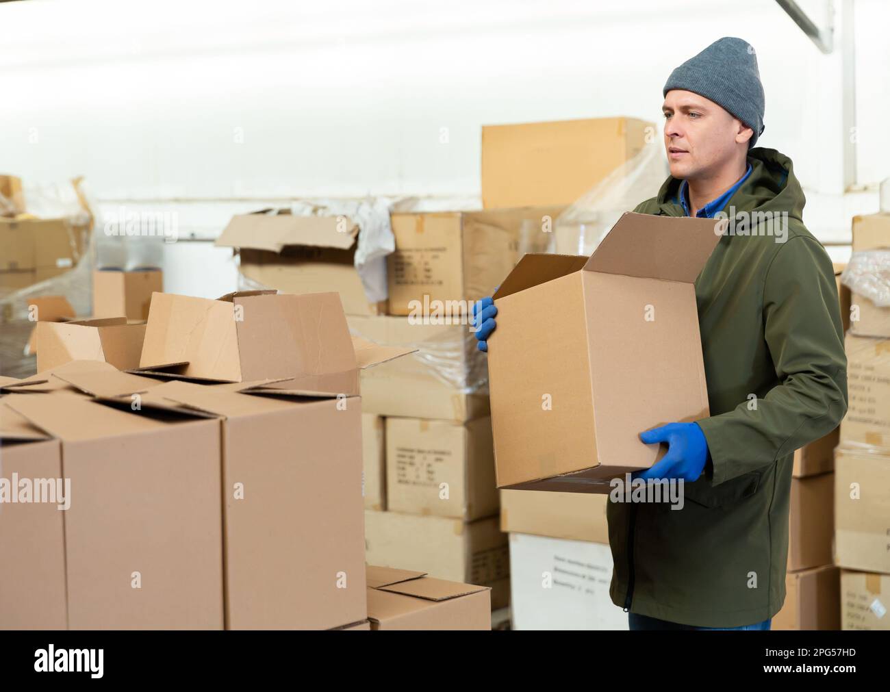 Loader stacks various boxes on racks in store Stock Photo - Alamy