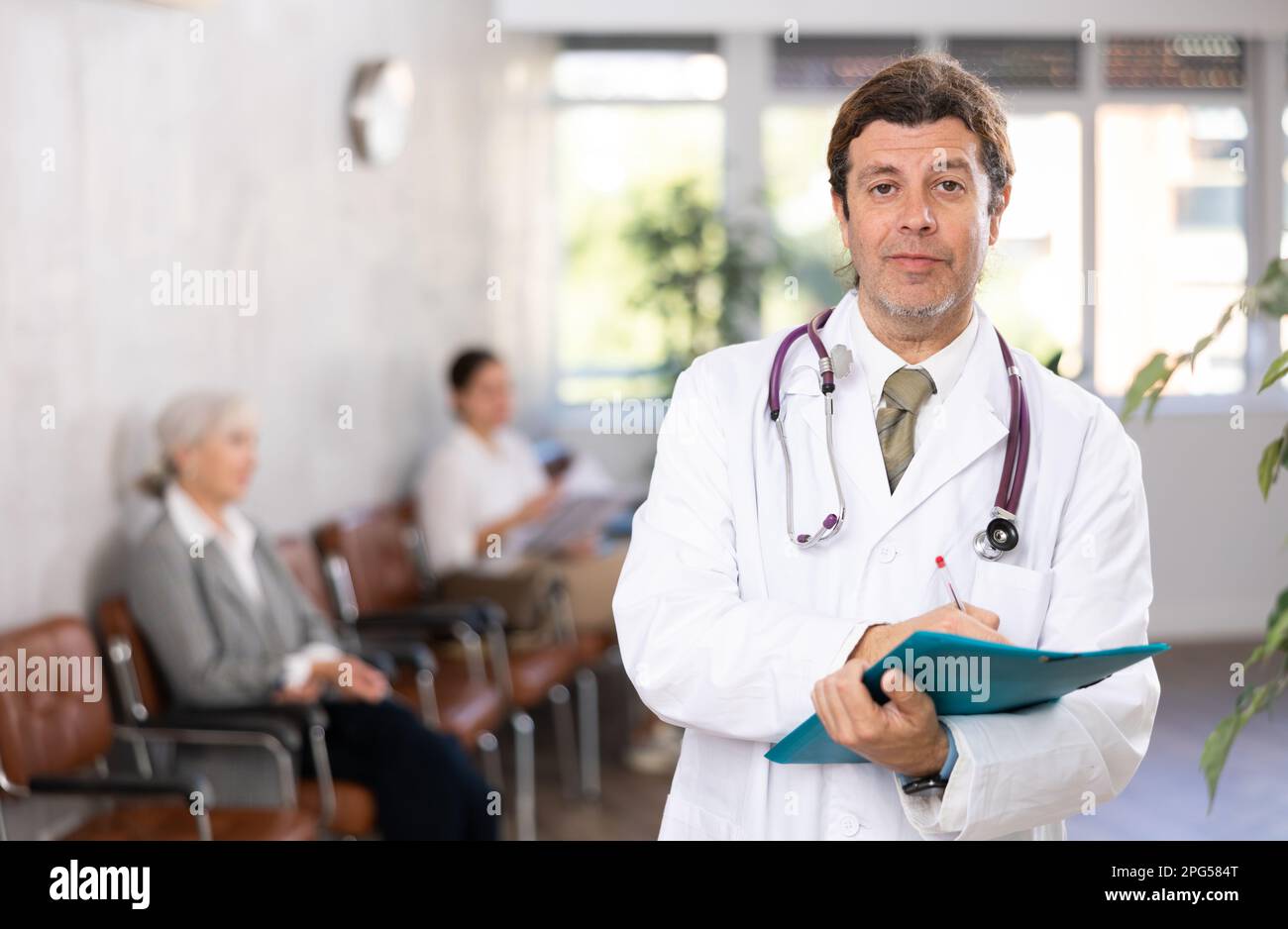 smiling male medical receptionist affably waiting for patients of ...